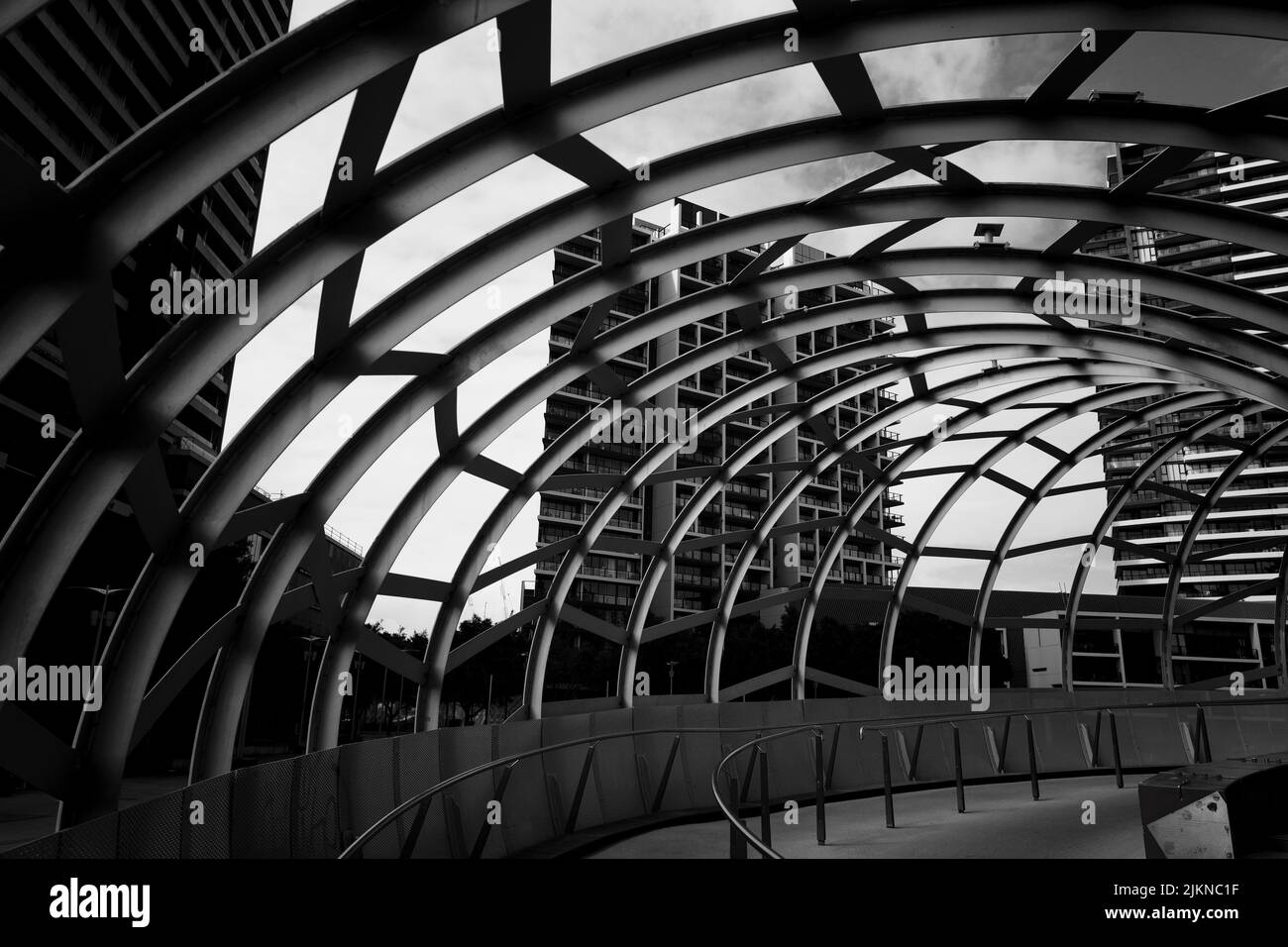 A grayscale shot of the arch design of a building and other buildings appearing outside Stock ...