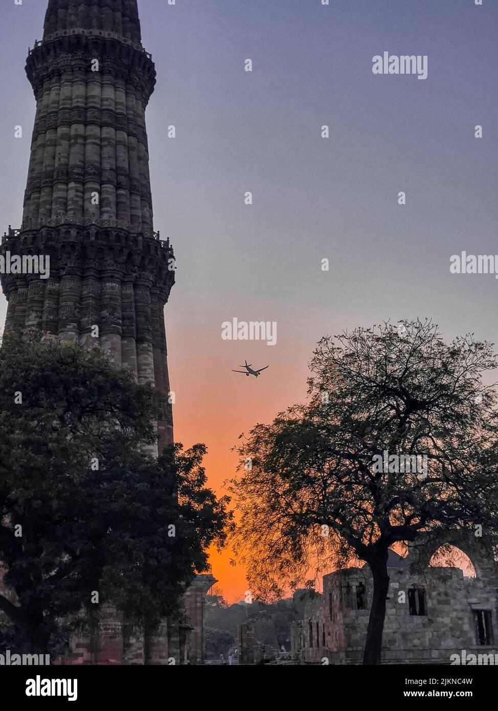 A beautiful view of an old Qutab Minar tower and an airplane flying in ...