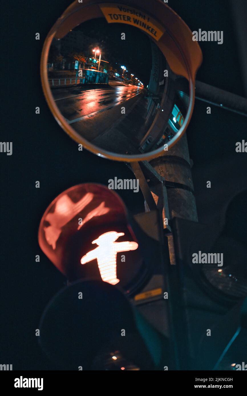 A vertical shot of red crossing light with mirror reflection at night ...