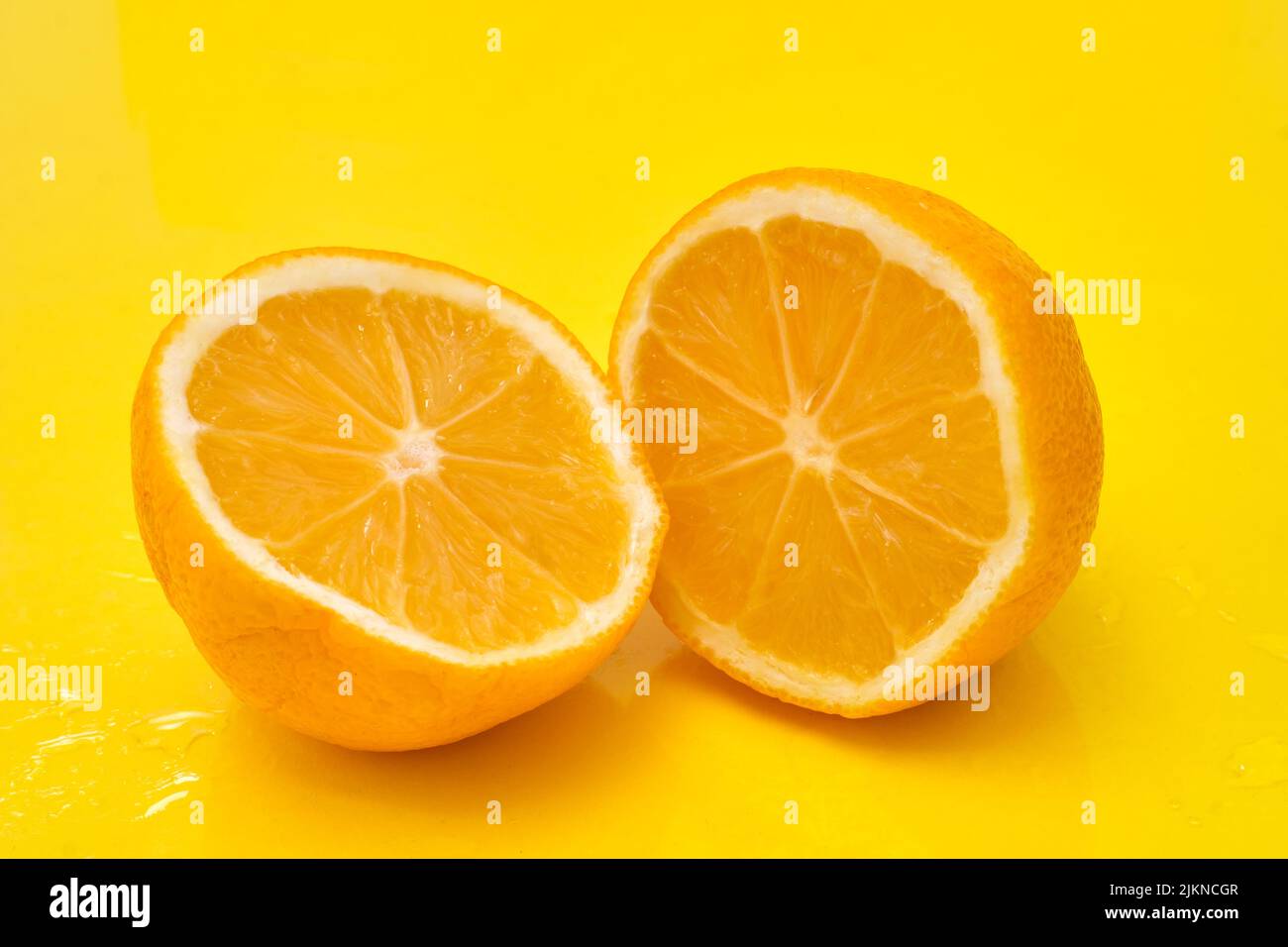 Two slices of lemon cut in half on yellow background Stock Photo - Alamy