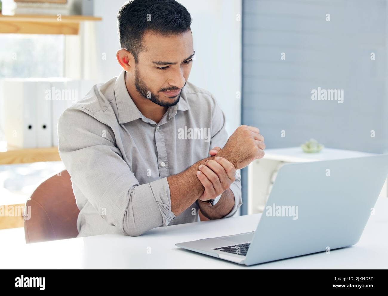 Listen to your body. a young man having pain in his wrist at work in a ...