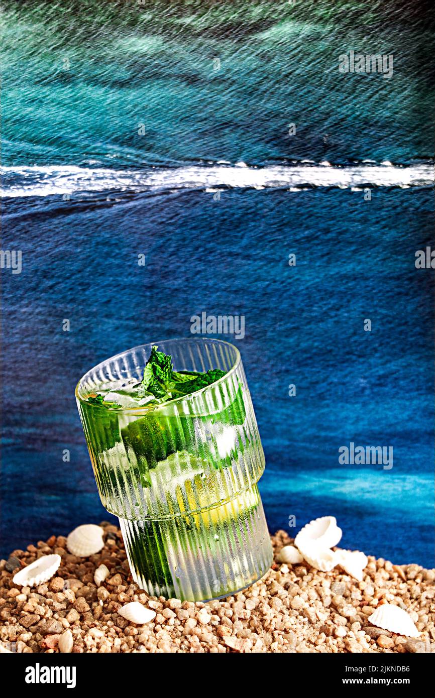 A vertical shot of a glass of alcoholic cocktail with lime on a pebble ...