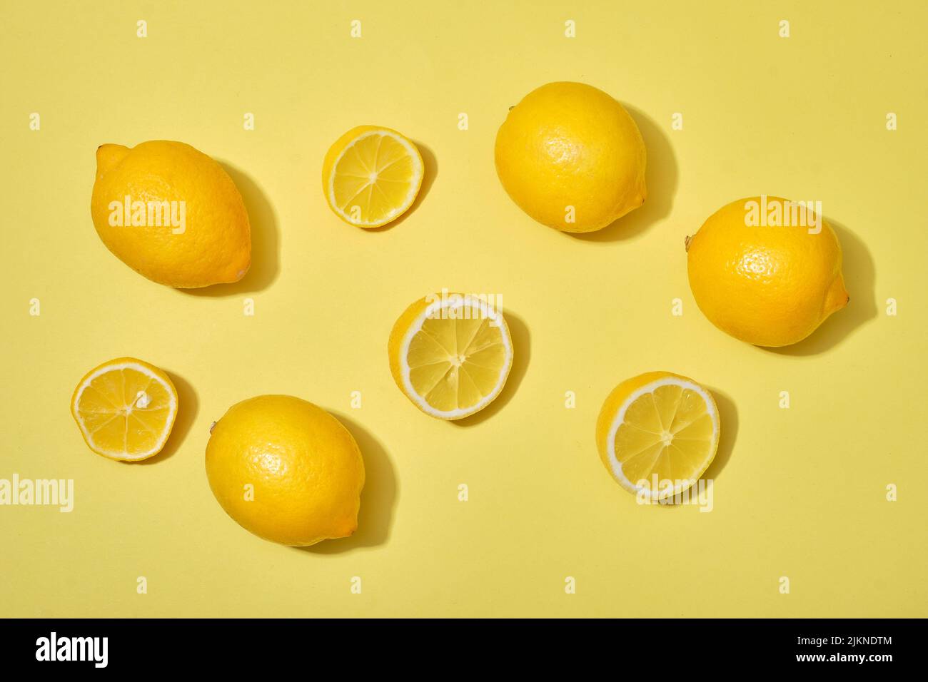 Lemon top view with halves and whole ripe lemons on yellow background ...