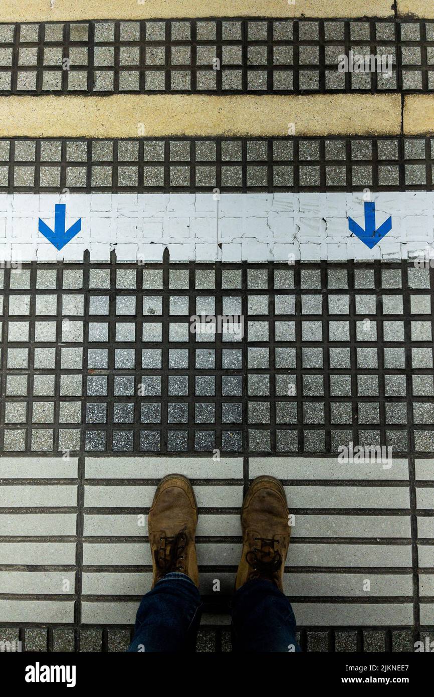 A vertical shot of man's feet on a pavement with small arrows Stock ...