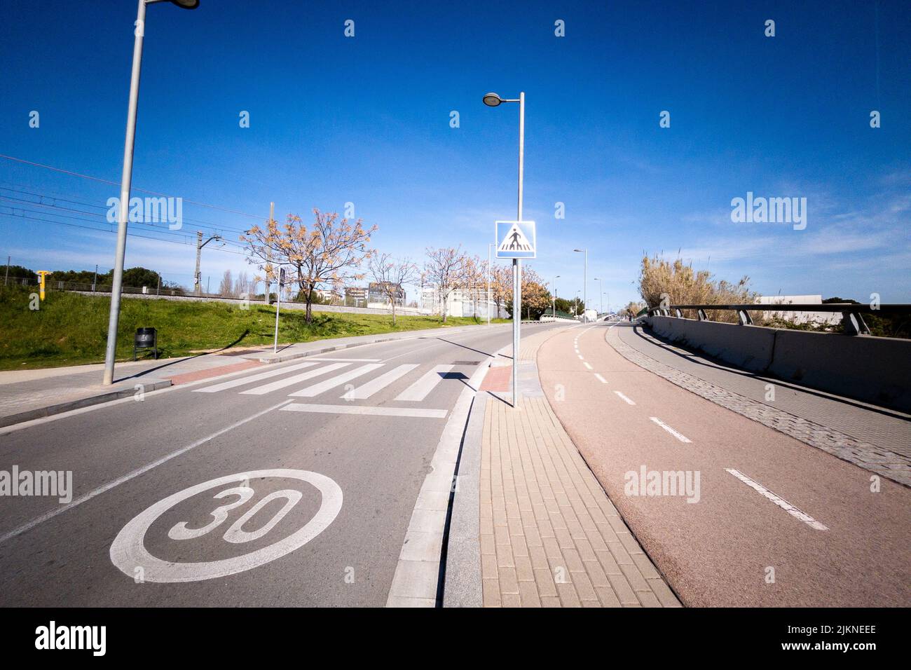 A photo of a road with road marking, street lamps and greenery in a ...