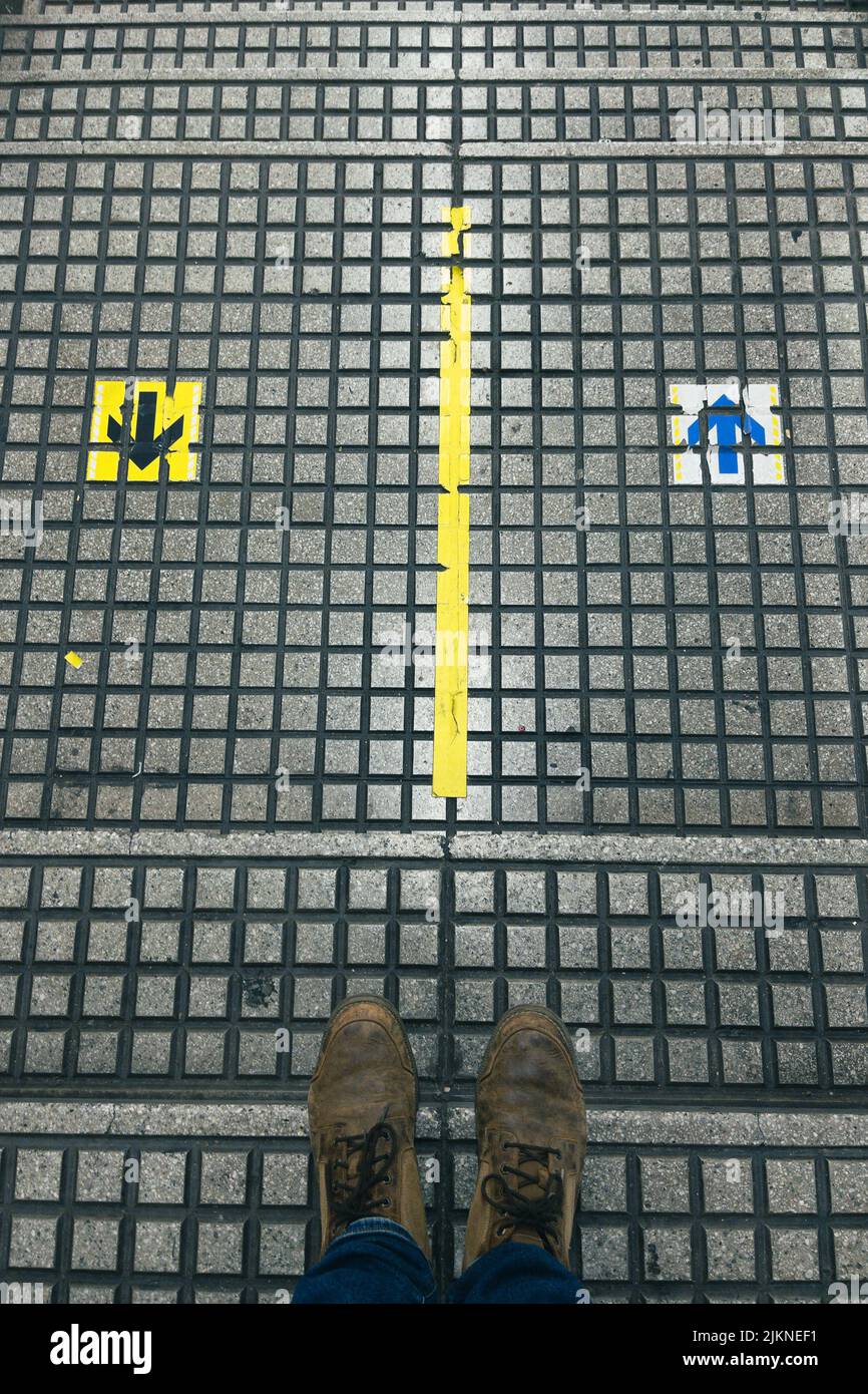 A vertical shot of man's feet on a pavement with small arrows Stock ...