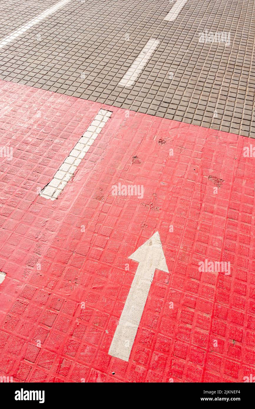 A vertical photo of an arrow sign on red cycle path Stock Photo - Alamy