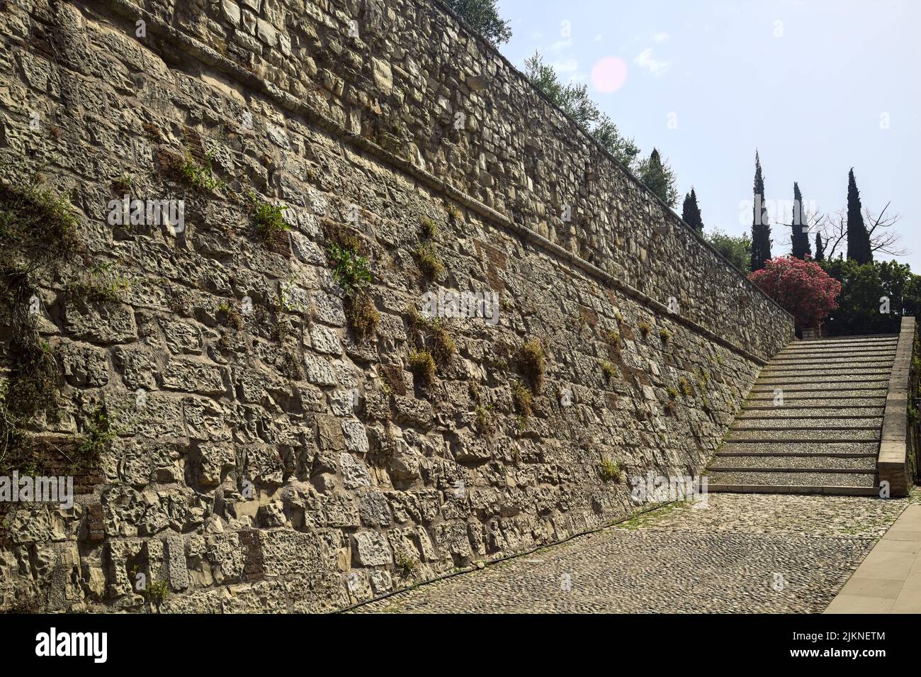 Cobbled passage and steps next to a stone wall in a castle on a sunny ...