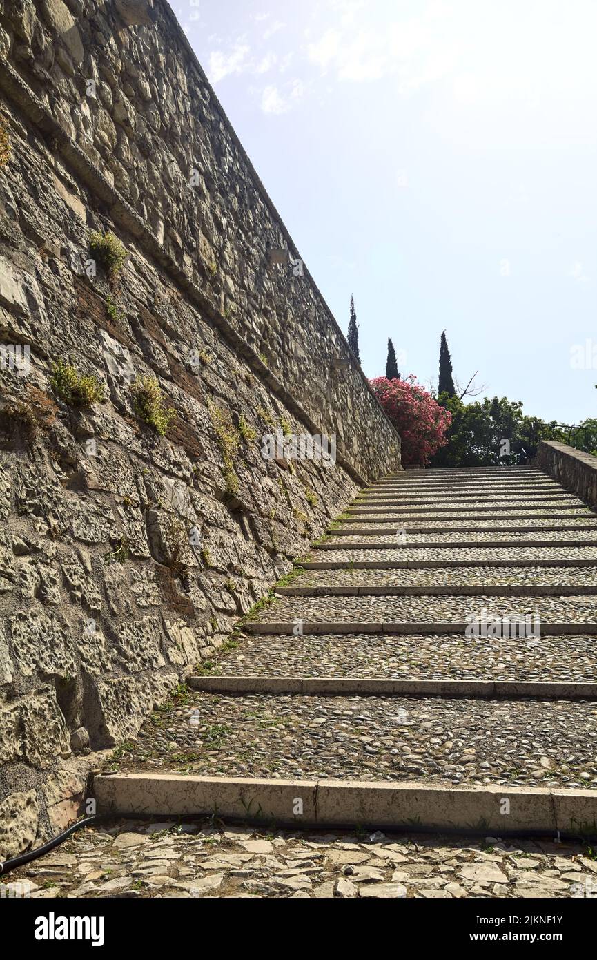 Cobbled passage and steps next to a stone wall in a castle on a sunny ...