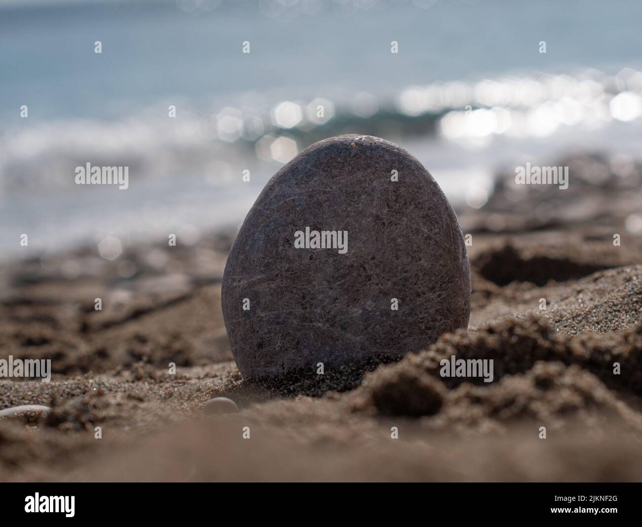 A closeup of a stone in the sand at the beach Stock Photo - Alamy