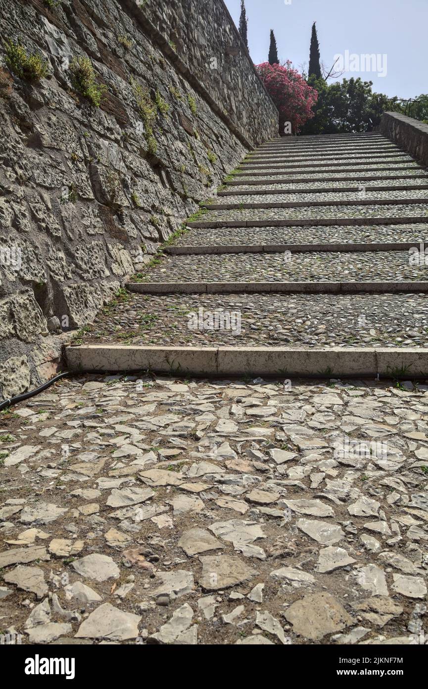 Cobbled passage and steps next to a stone wall in a castle on a sunny ...