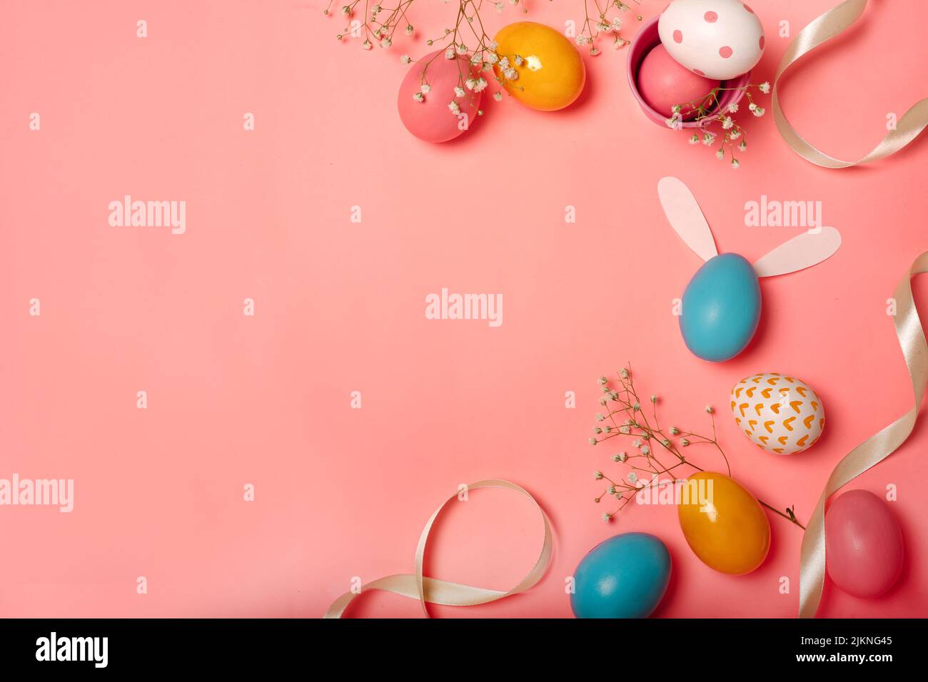A top view of colorful Easter eggs and decorations on a pink background ...