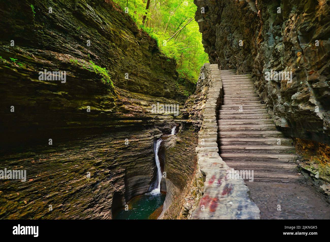 A rocky staircases near flowing waterfall among steep cliffs in Watkins ...