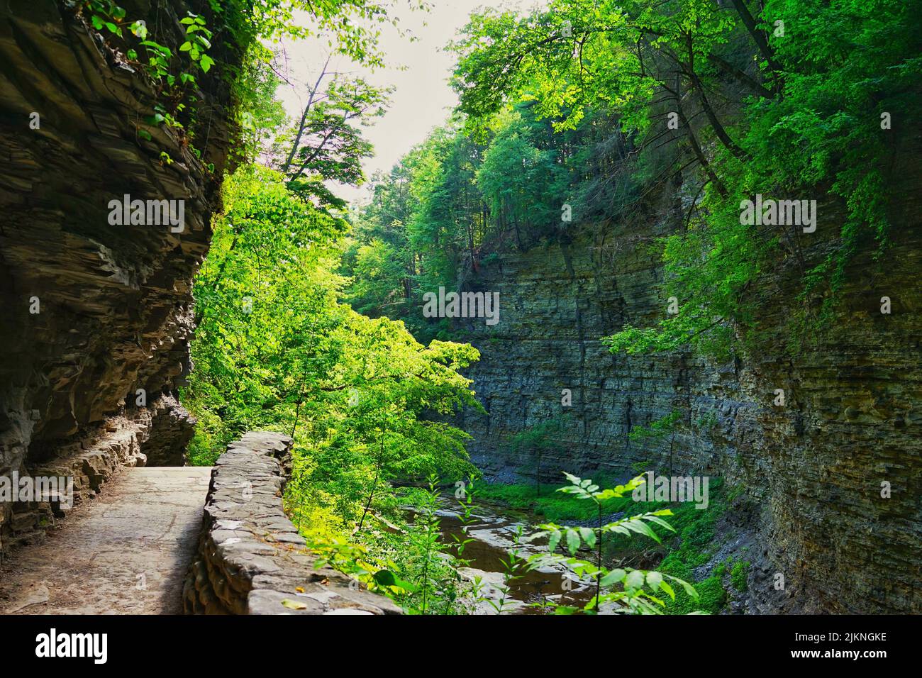 A rocky footpath near flowing water among steep cliffs in Watkins Glen ...
