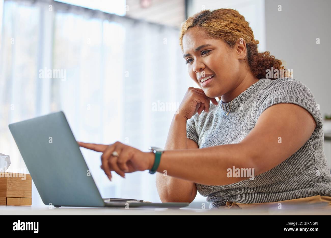 Confused businesswoman reading an email on a laptop indoors. One young ...