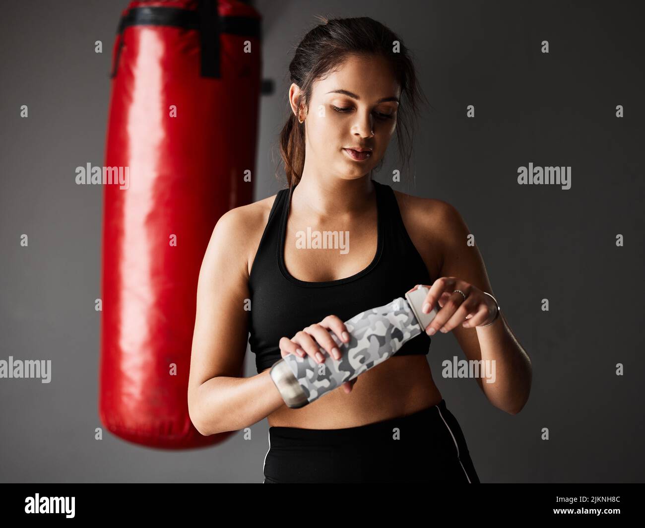 Staying hydrated. an attractive young female boxer drinking water while ...
