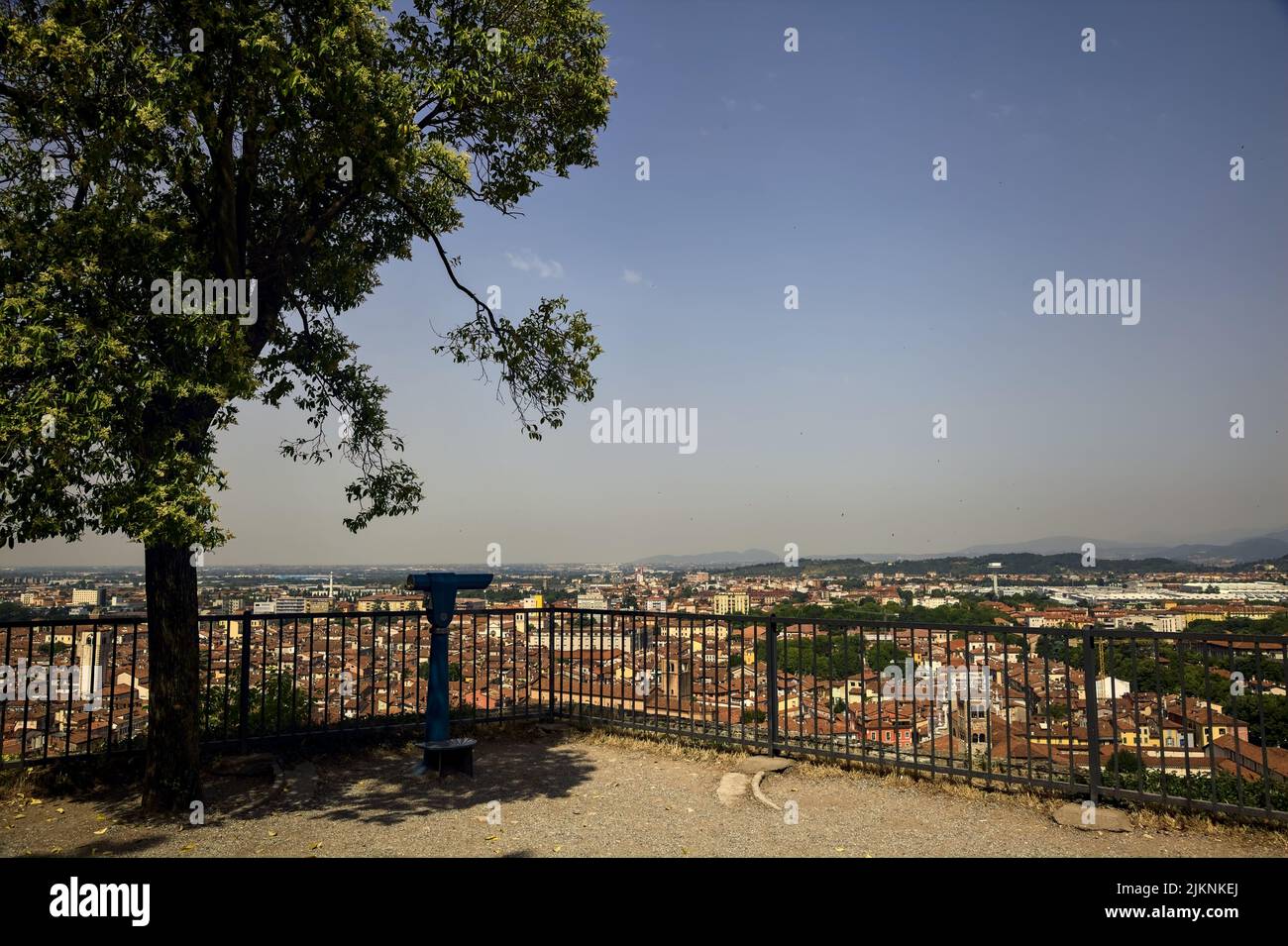 Viewpoint with a coin operated eyeglass under a tree above a city on a ...