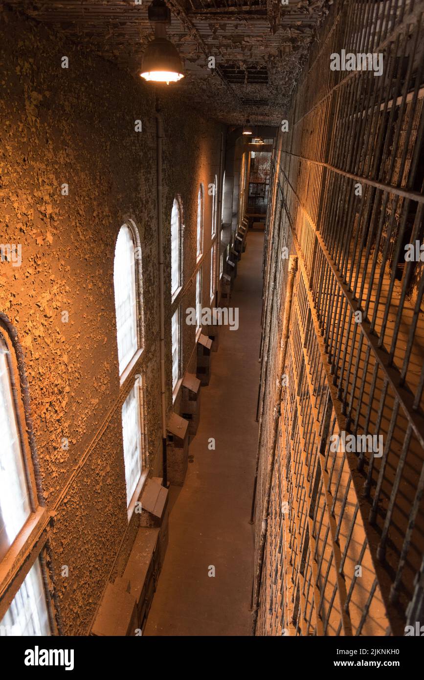 A vertical shot of a long corridor in a wethered prison with rusty ...