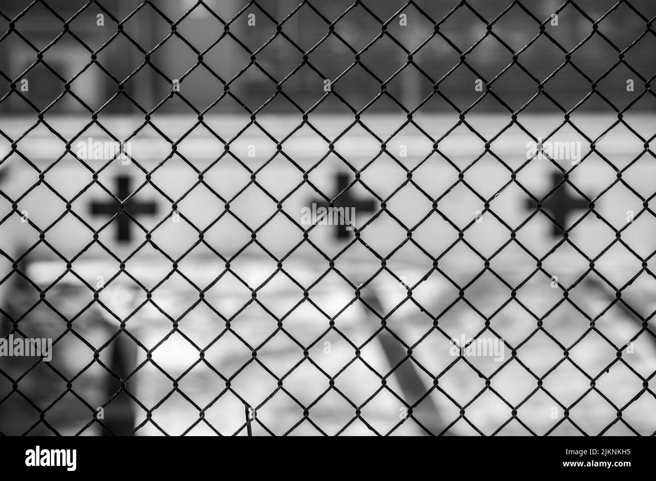 A grayscale shot of a gate with crosses behind in St. Anne's Hill in ...
