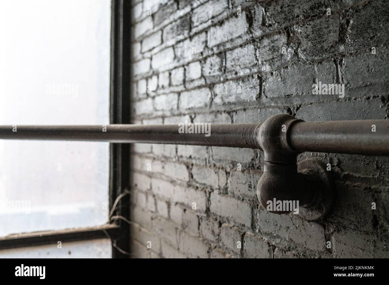 A closeup of a pipe attached to the brick wall near the window Stock ...