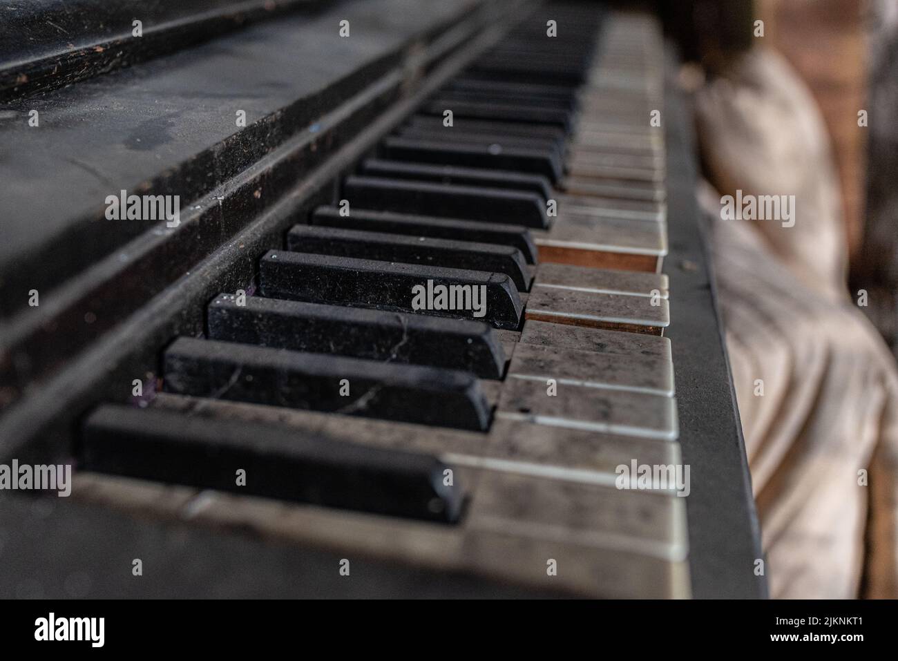 A broken vintage piano with dirty piano keys in an abandoned warehouse ...
