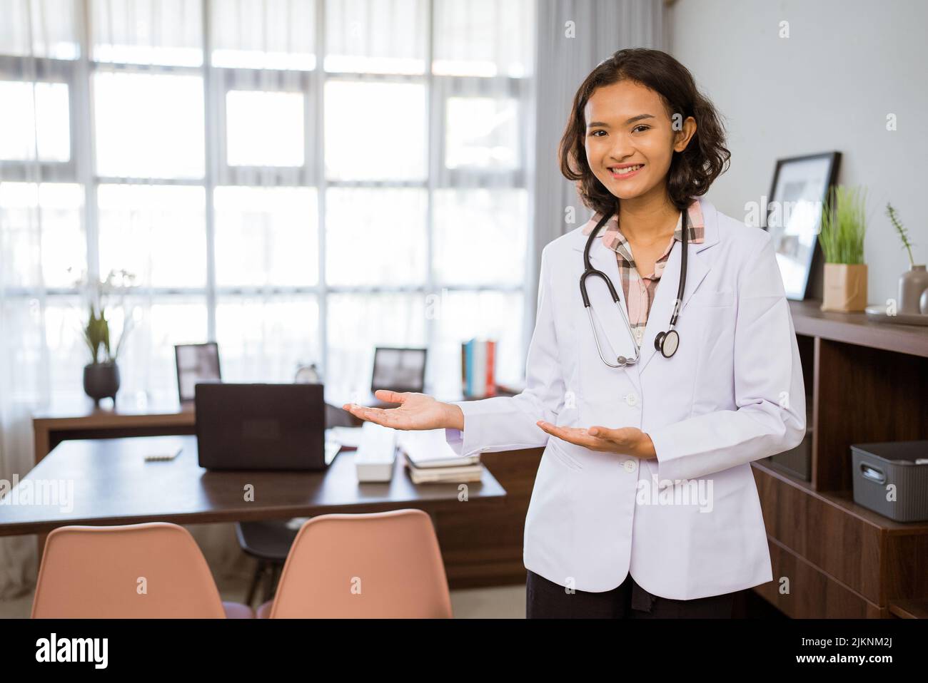 Young asian female doctor standing with hand gesture presenting ...