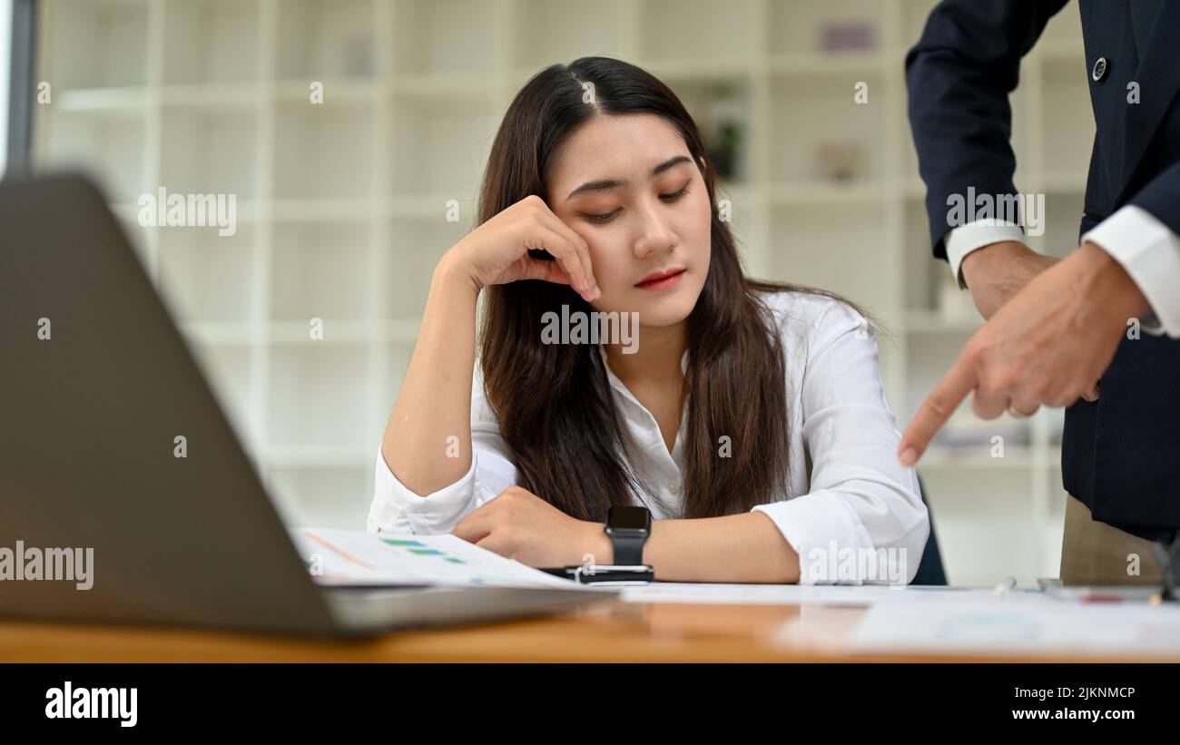 Tired and bored young Asian businesswoman or female office worker ...