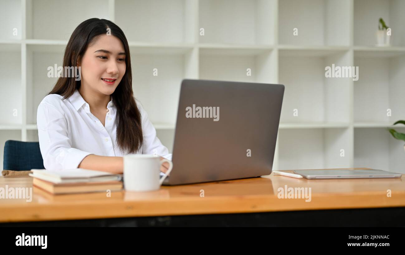 Attractive young Asian businesswoman or female assistant using laptop ...