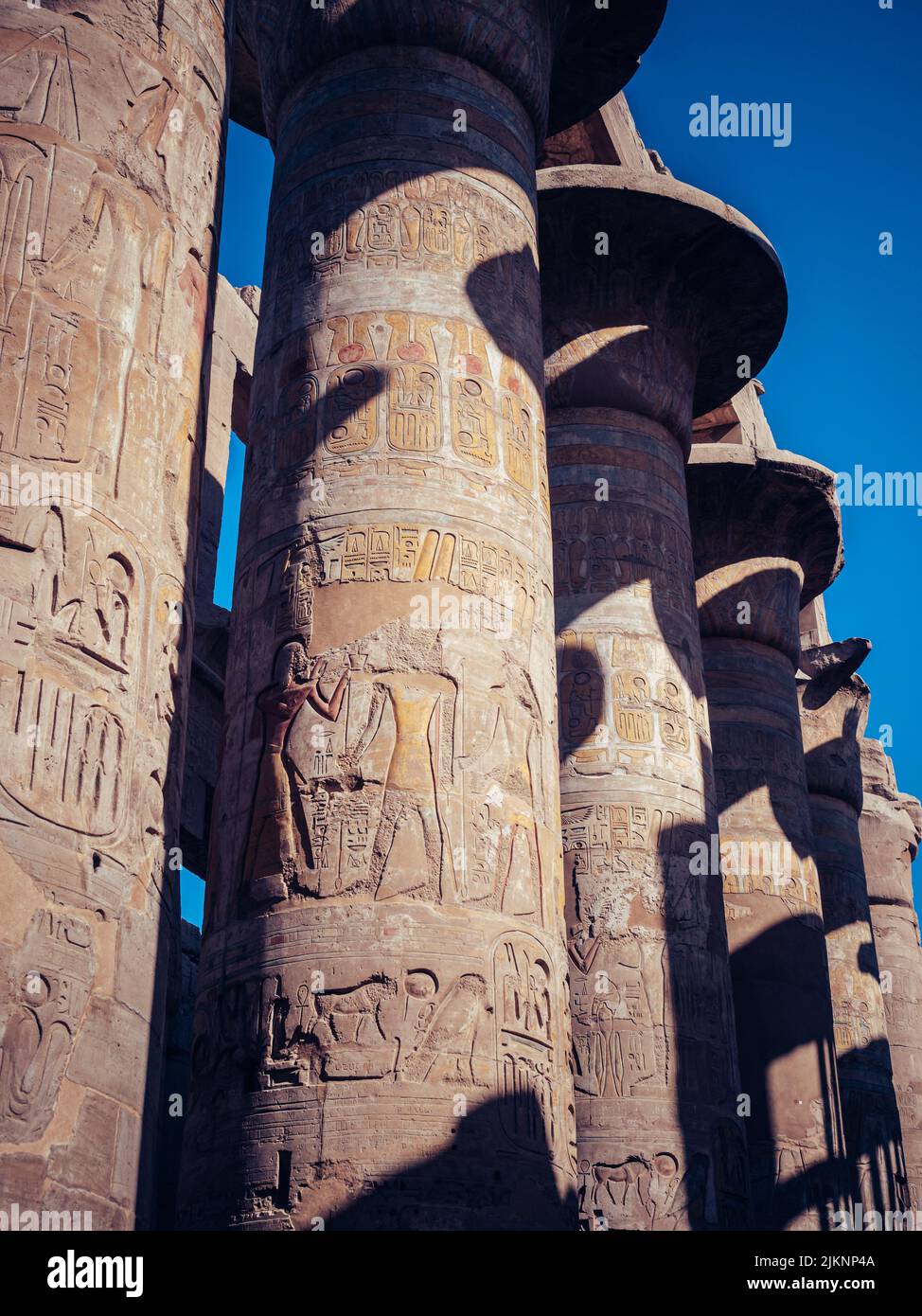A vertical shot of the columns with carvings in the ancient Karnak ...