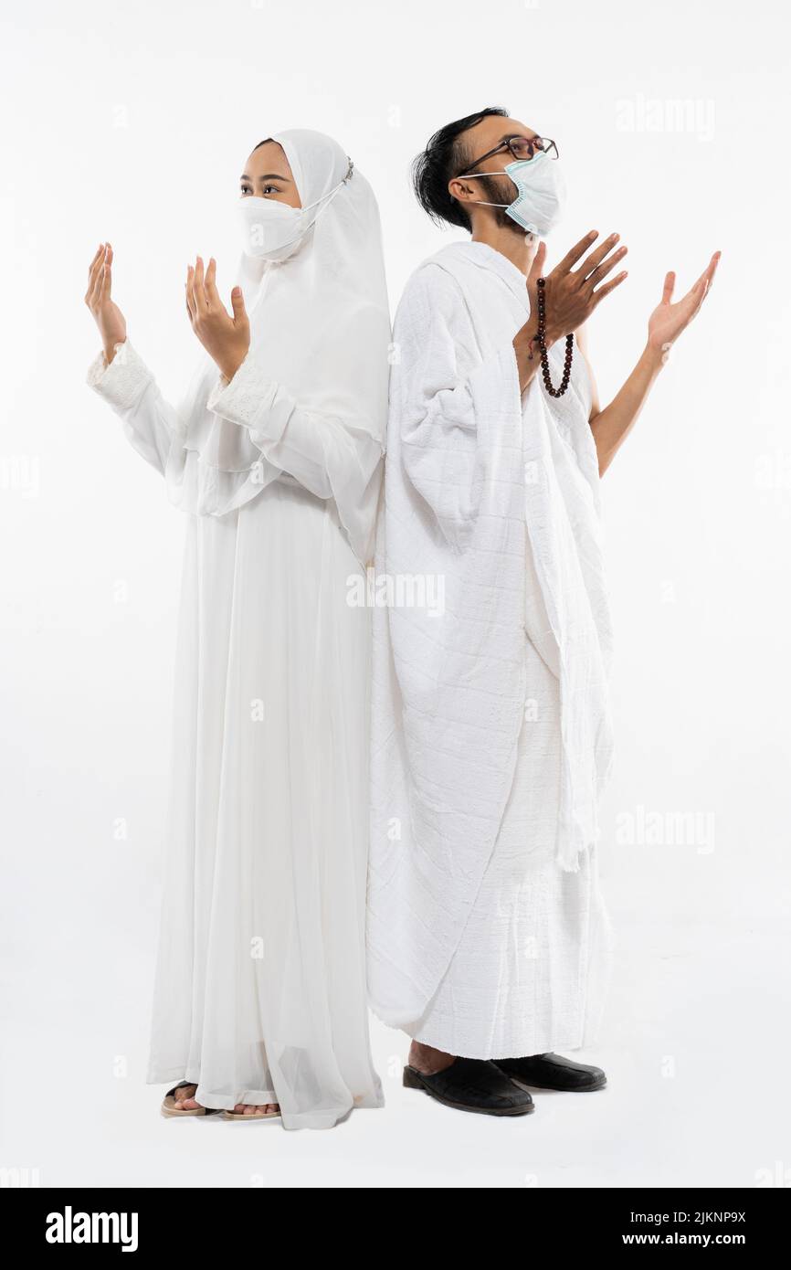 Couple wearing hajj ihram clothes praying with hands looking up Stock ...