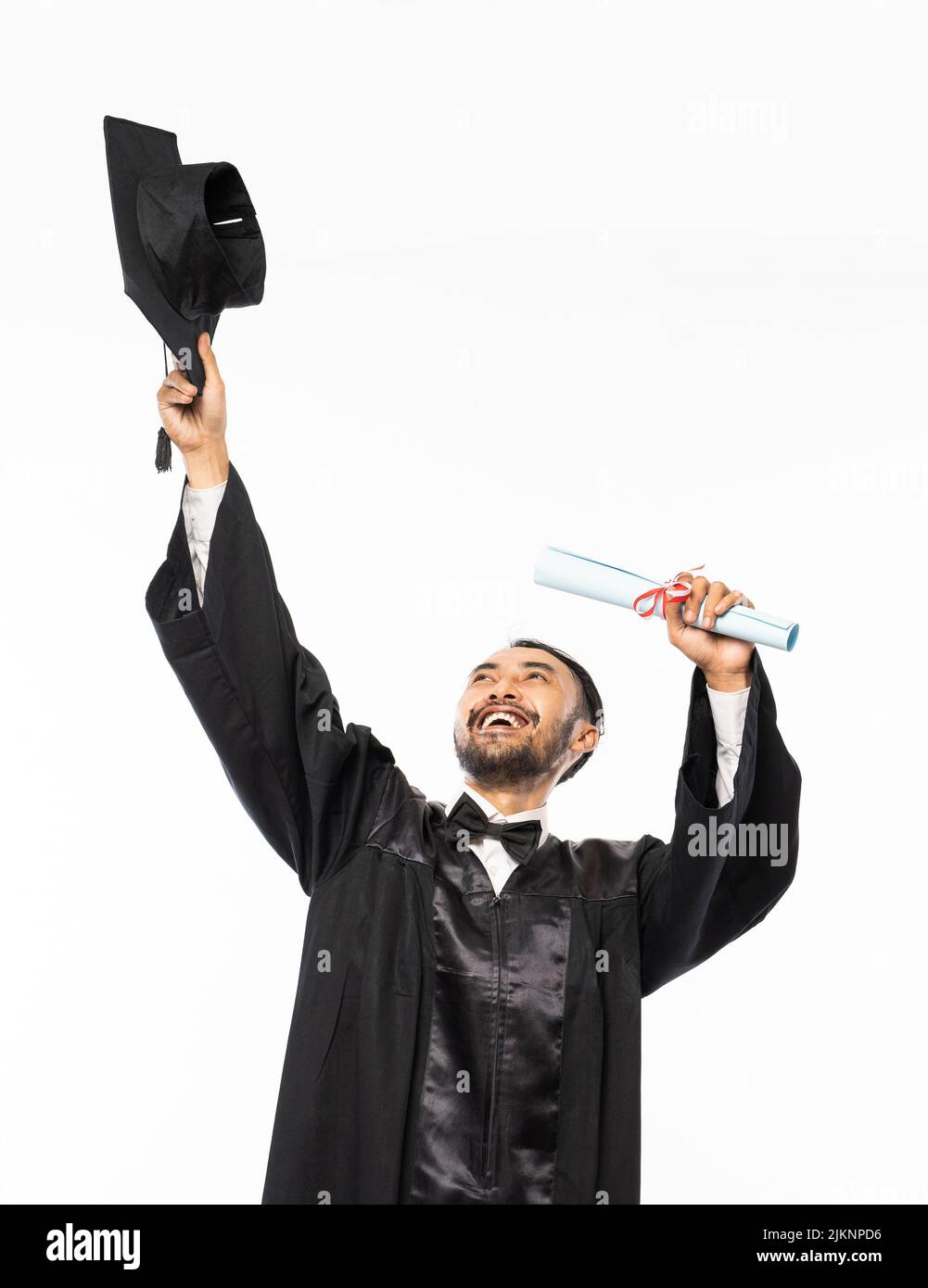 Happy graduate in black toga holding up his hat Stock Photo - Alamy