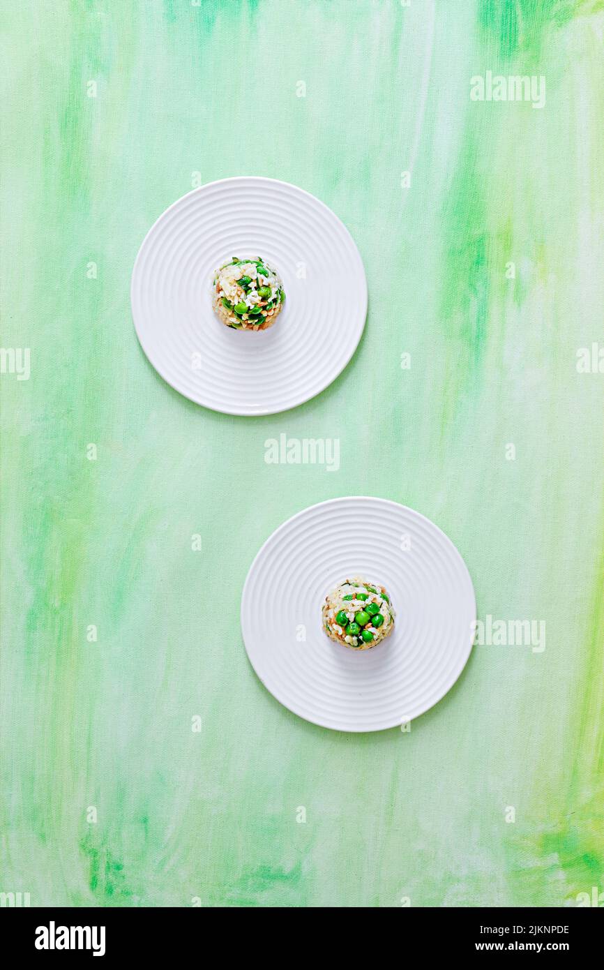 A top view of two plates of a small portion of fried rice on a green ...