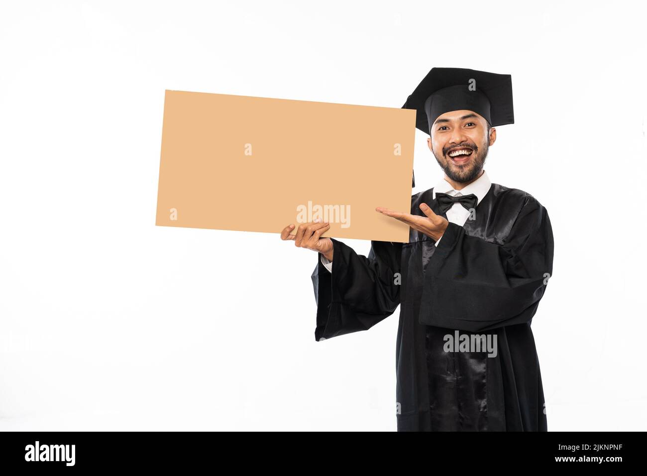 Excited graduate male students wearing toga holding blank space carton ...