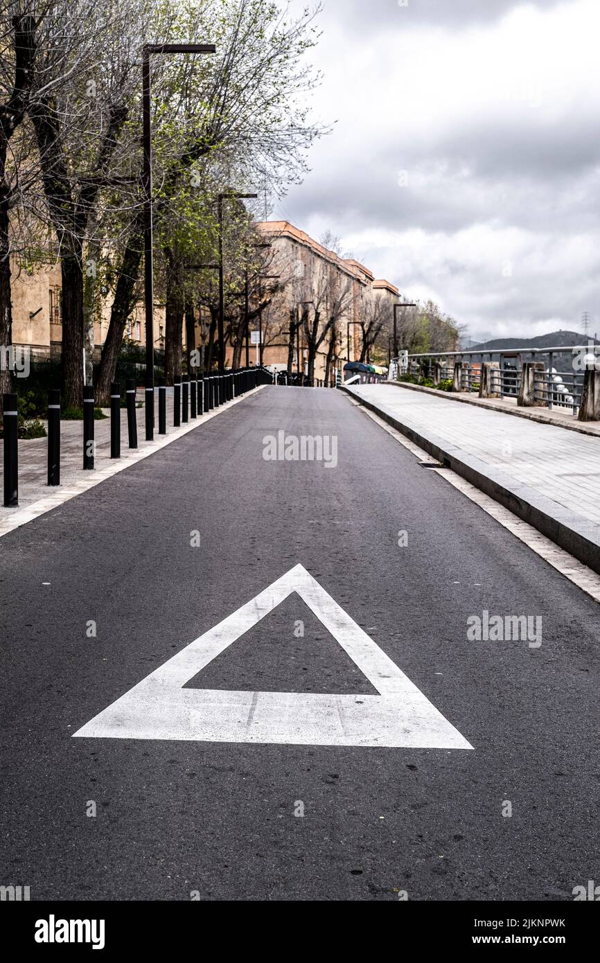 A vertical closeup of a traffic sign with an arrow on an asphalt road ...
