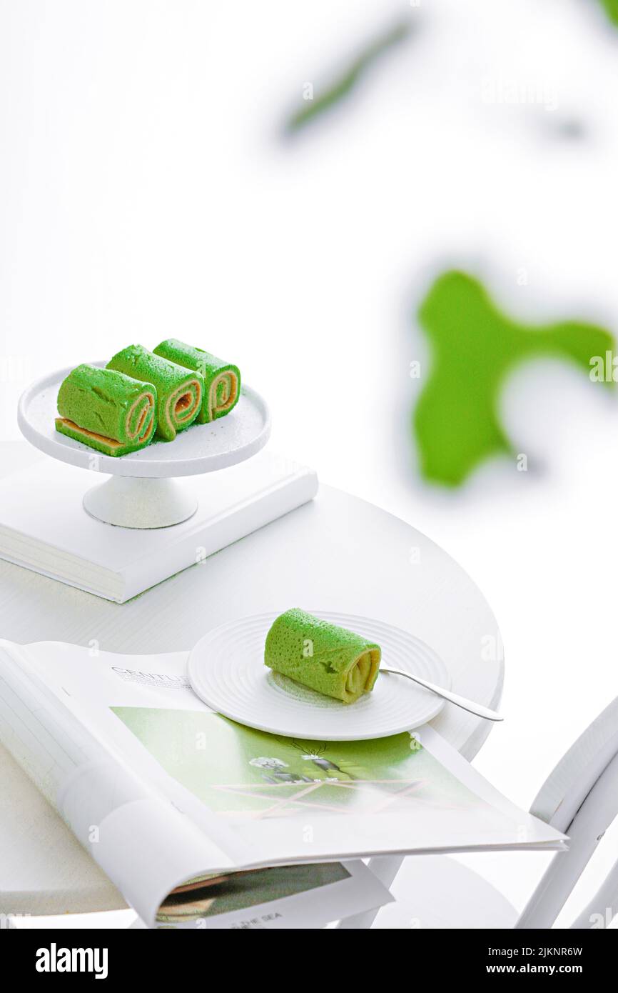 A top view of a tasty Matcha Swiss Roll on a white plate on a blurred ...