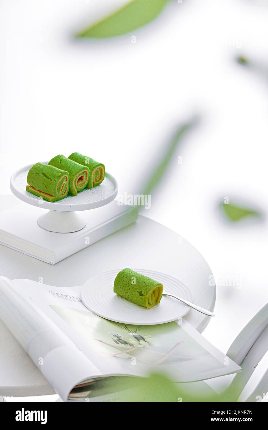 A top view of a tasty Matcha Swiss Roll on a white plate on a blurred ...