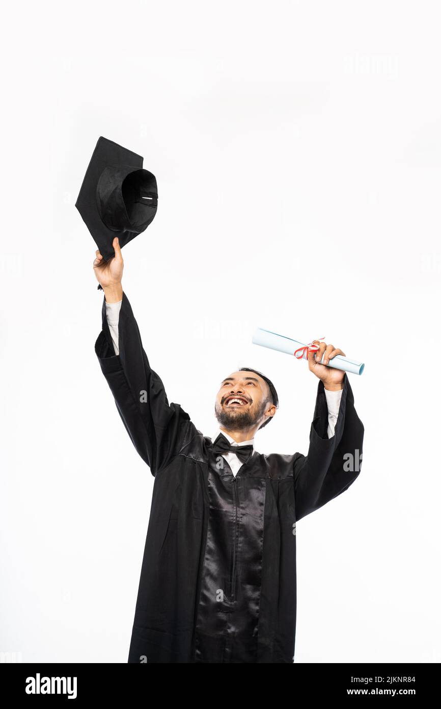 Happy graduate in black togas holding up toga hat Stock Photo - Alamy
