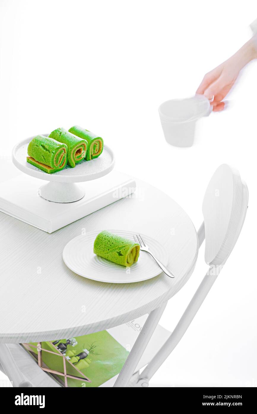 A top view of a tasty Matcha Swiss Roll on a white plate on a white ...