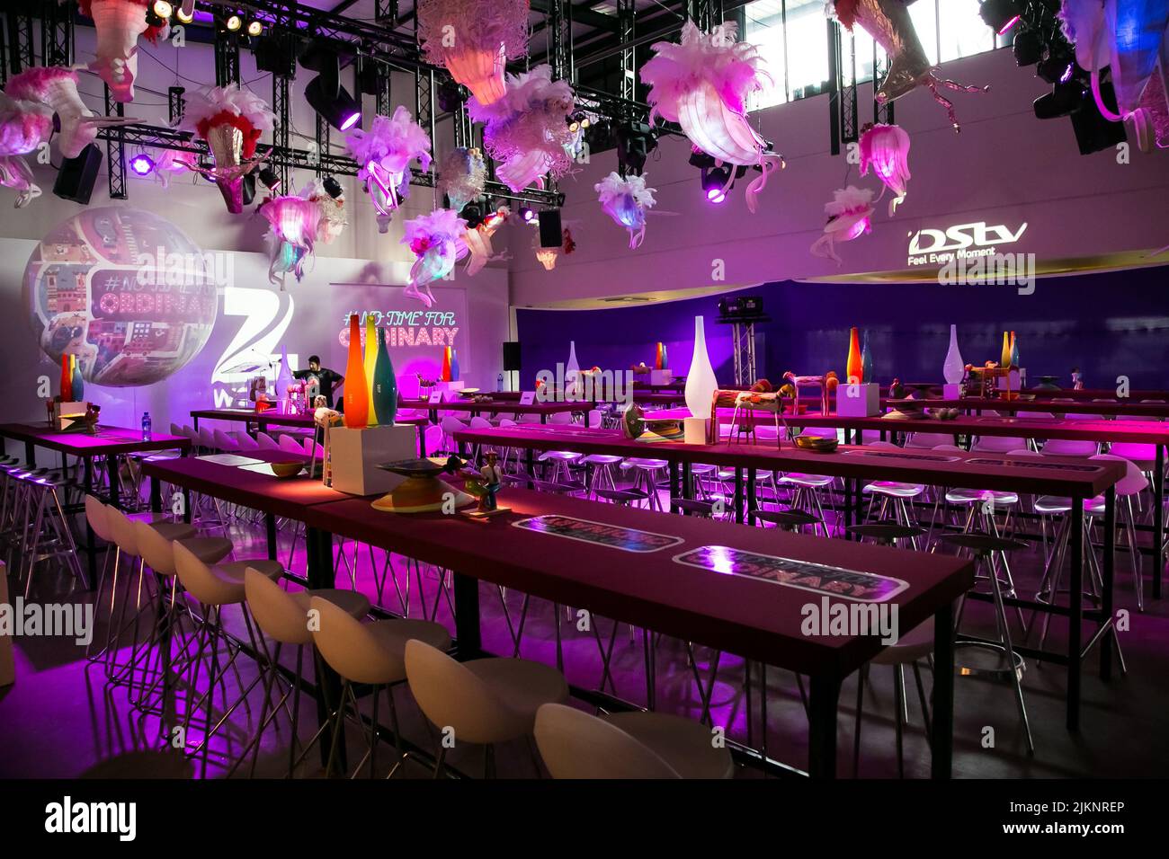 A purple themed decoration on stage lighting equipment over bar chairs ...