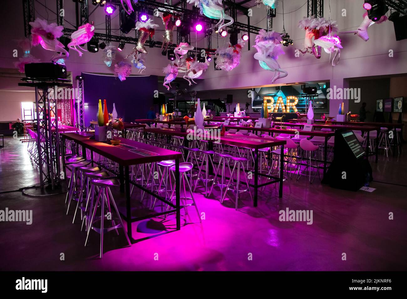 A purple themed decoration on stage lighting equipment over bar chairs ...