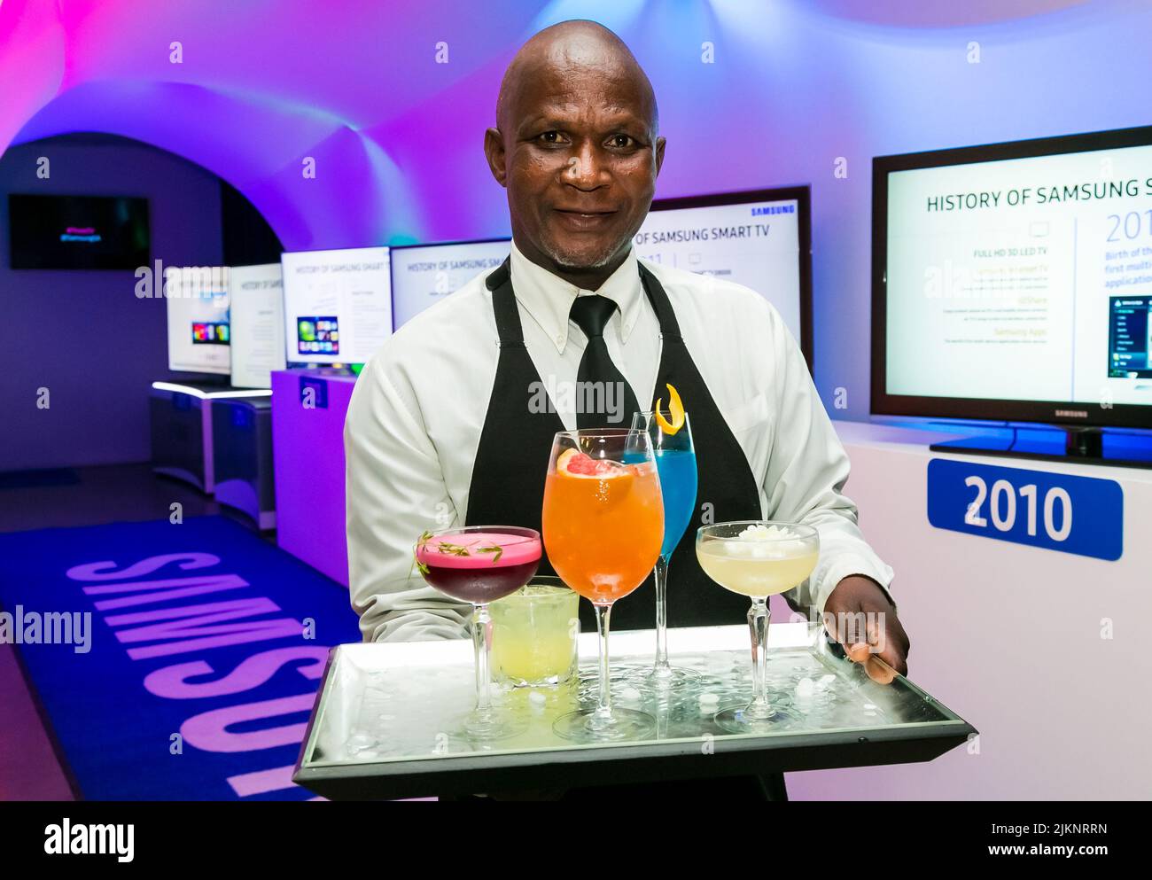 An African male waiter holding a tray at a corporate event in ...