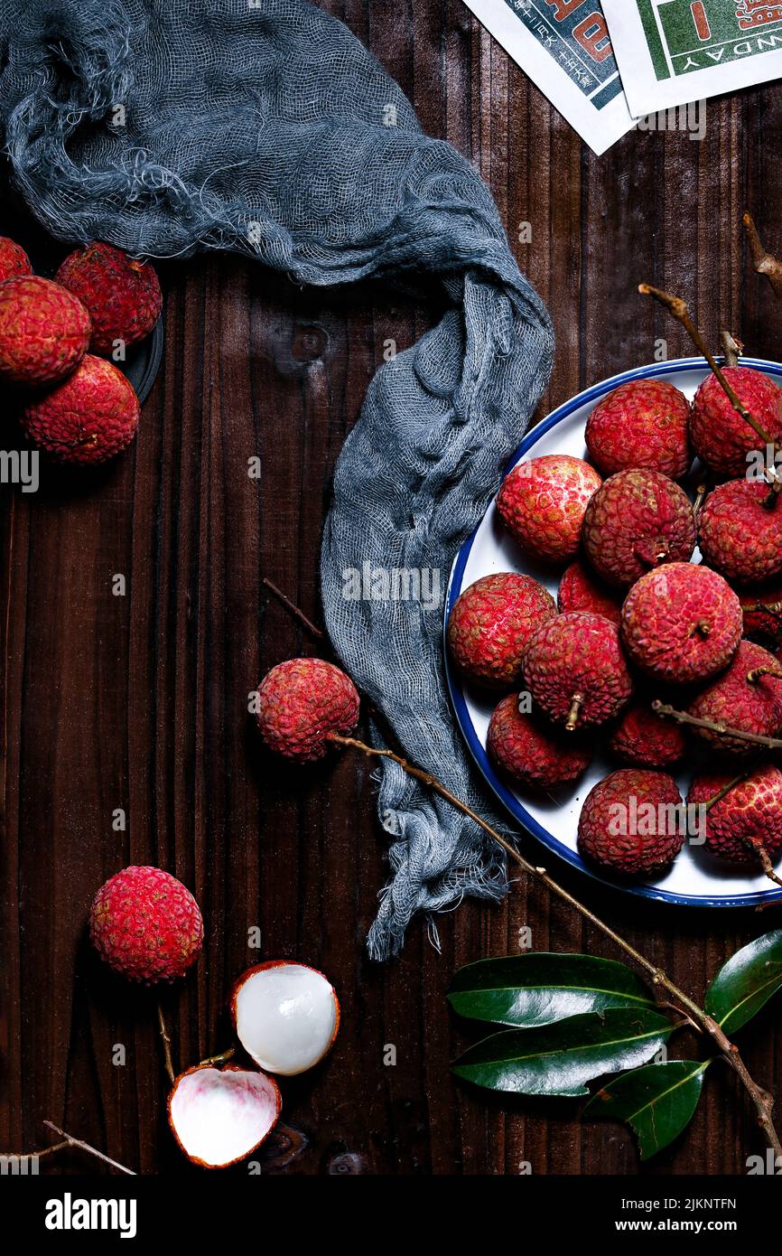A vertical closeup of the Lychee fruits on the wooden table. Top view ...