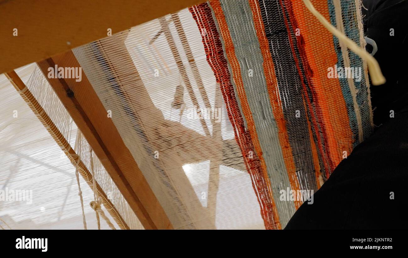 A view from underneath a traditional weaving loop of a person working ...