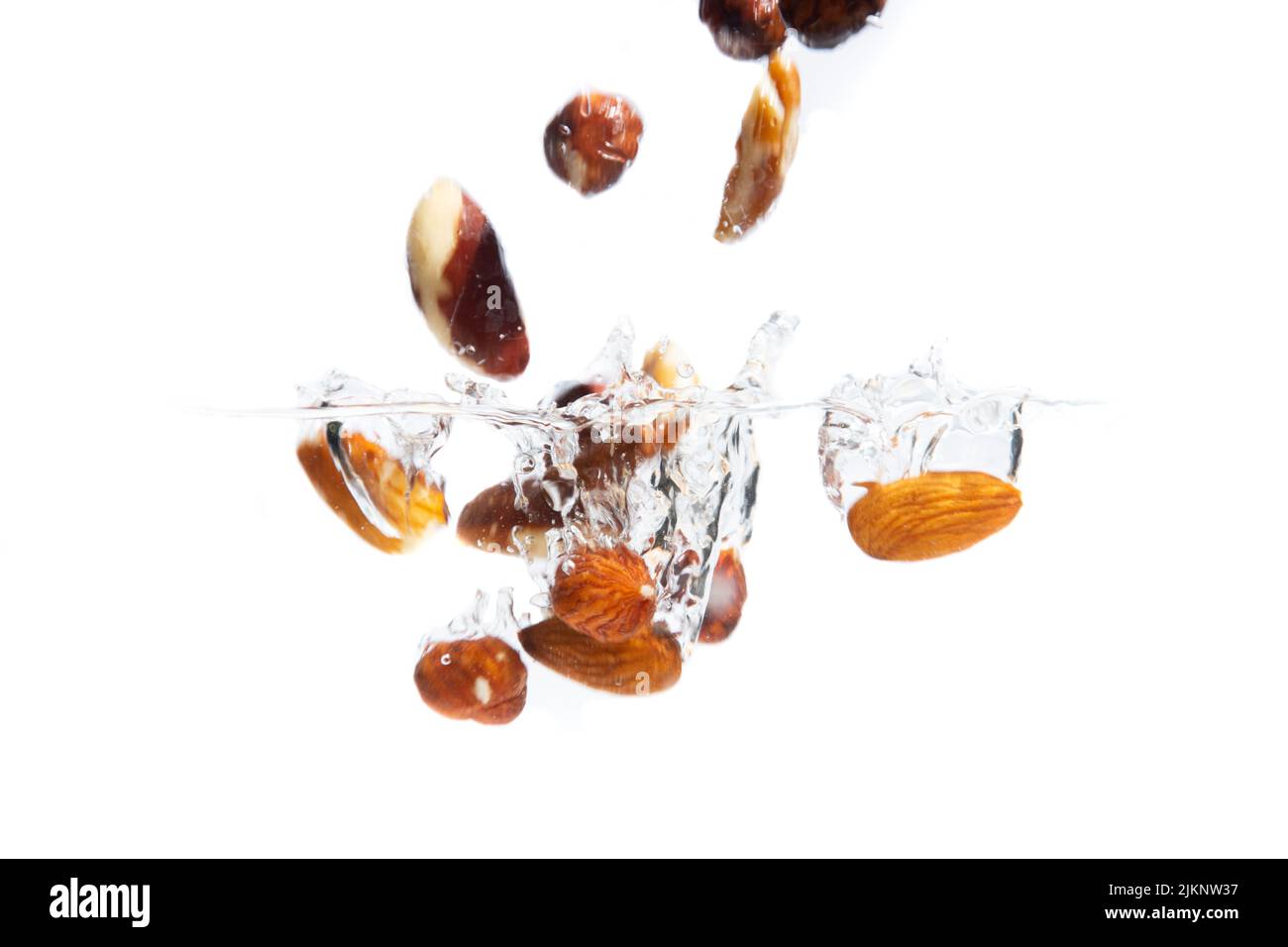A closeup of an assortment of candied nuts dropping into water on a ...