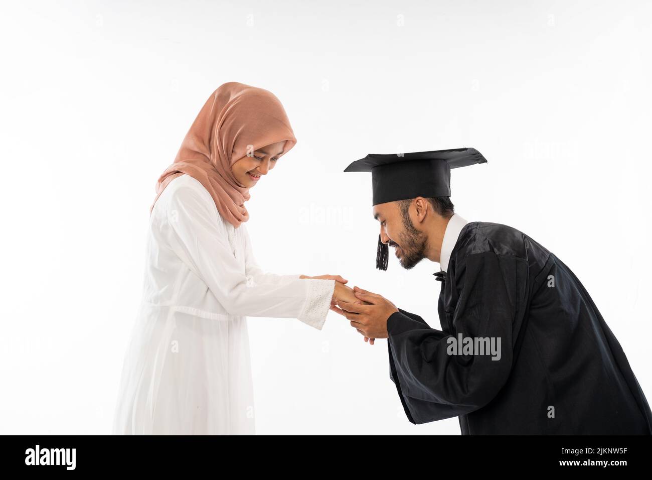 Asian male graduate student wearing toga shaking hands with mother ...