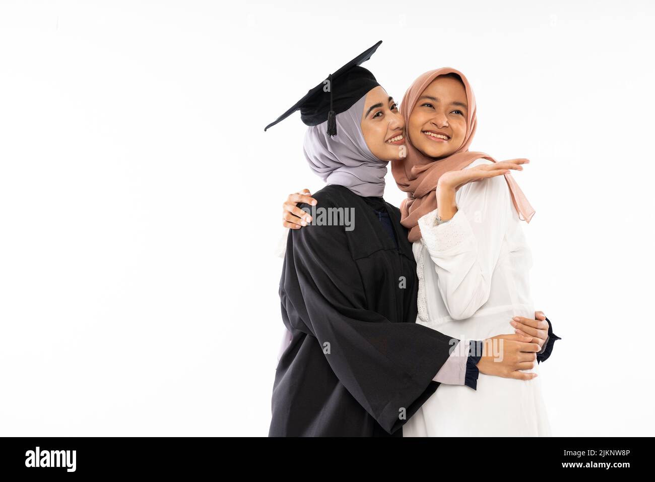 Happy asian female graduate student wearing toga hugging her friend ...