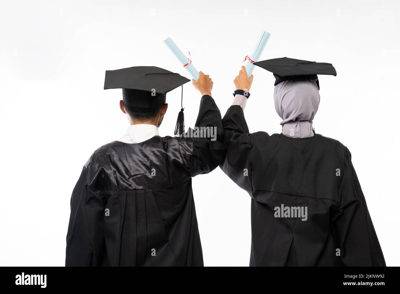 Rear view of two graduate students while holding up diplomas Stock ...