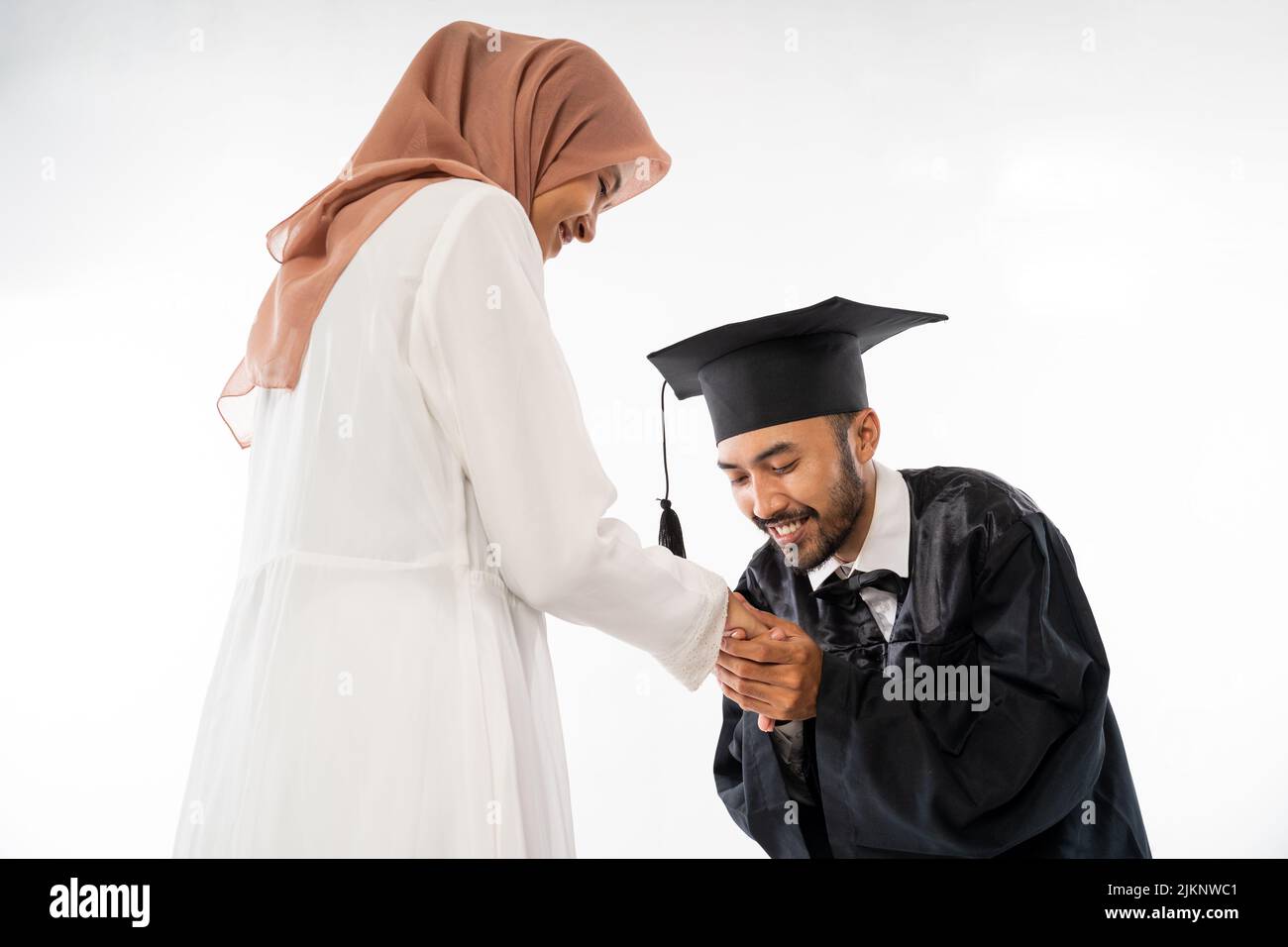 Asian male graduate student wearing toga shaking hands with mother ...