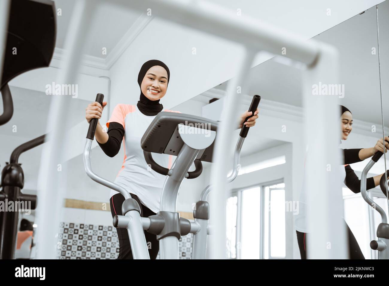 muslim women at the gym doing exercises on static elliptical cycle ...