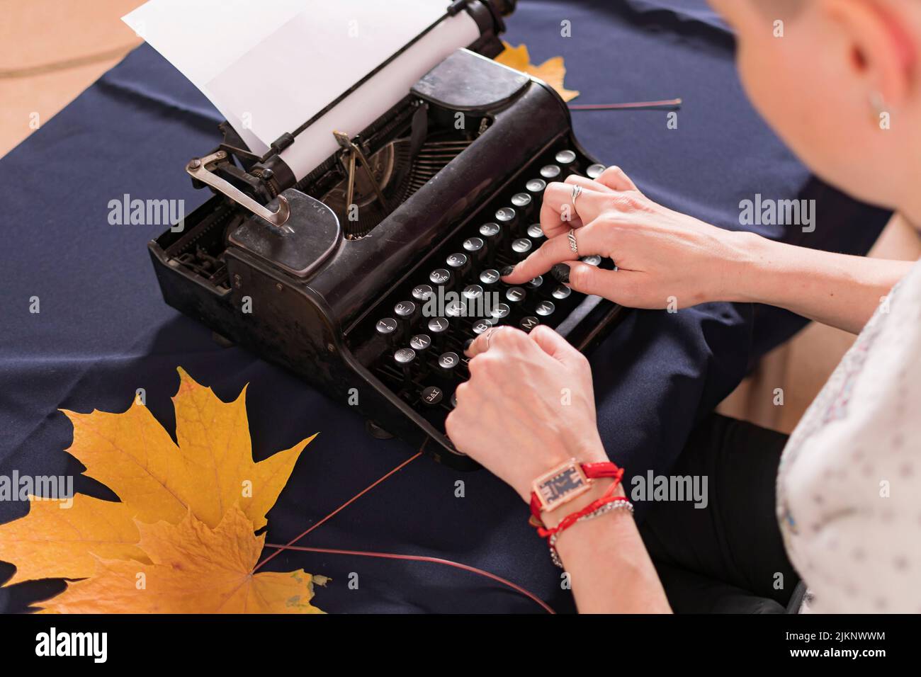 Cropped hands of young girl are typing on old typewriter. Office worker ...